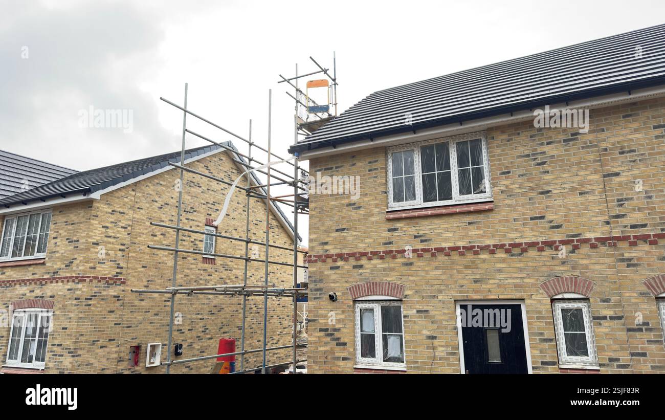 Two adjacent brick houses under construction. One house features ...