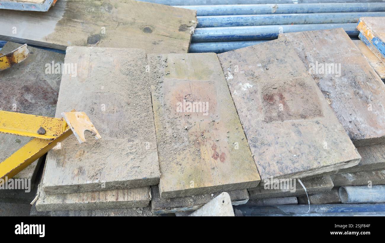 A close-up shows several dirty, weathered wooden planks stacked ...