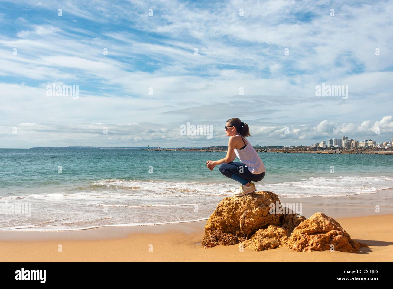 woman sitting on a rock by the sea looking at the view, getting away ...