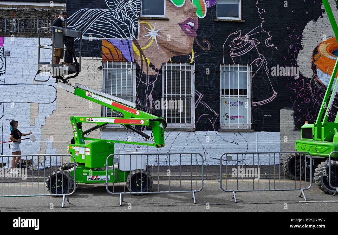 Man of lift and woman on ground painting their own murals as part of ...