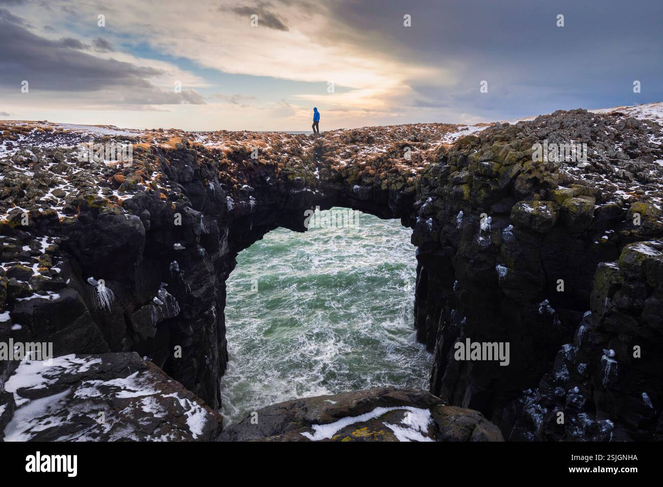 View of a man standing on the Stone Bridge. Arnarstapi, Snaefellsnes ...