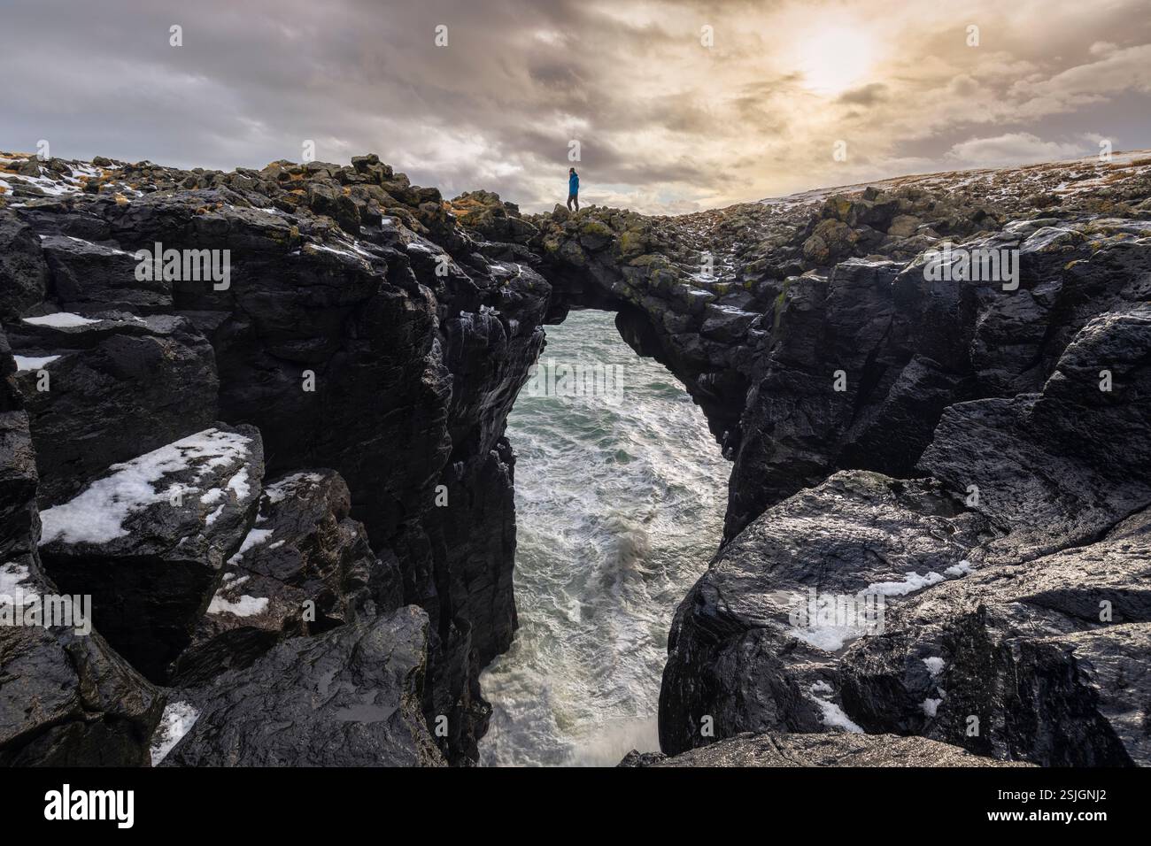 View of a man standing on the Stone Bridge. Arnarstapi, Snaefellsnes ...