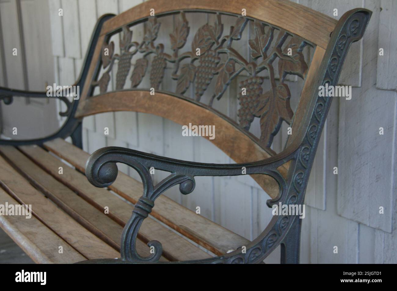 A decorative wood and metal bench on a front porch. Decorated with ...