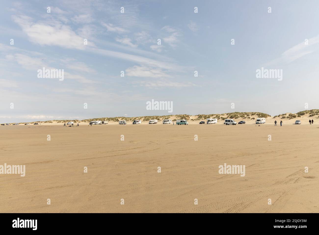 Tire tracks in the foreground and many cars in the background on the ...