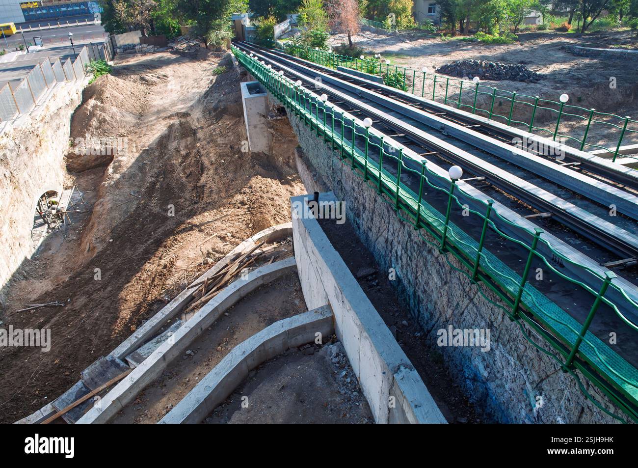 A high-angle shot shows the railway tracks, retaining walls, and ...