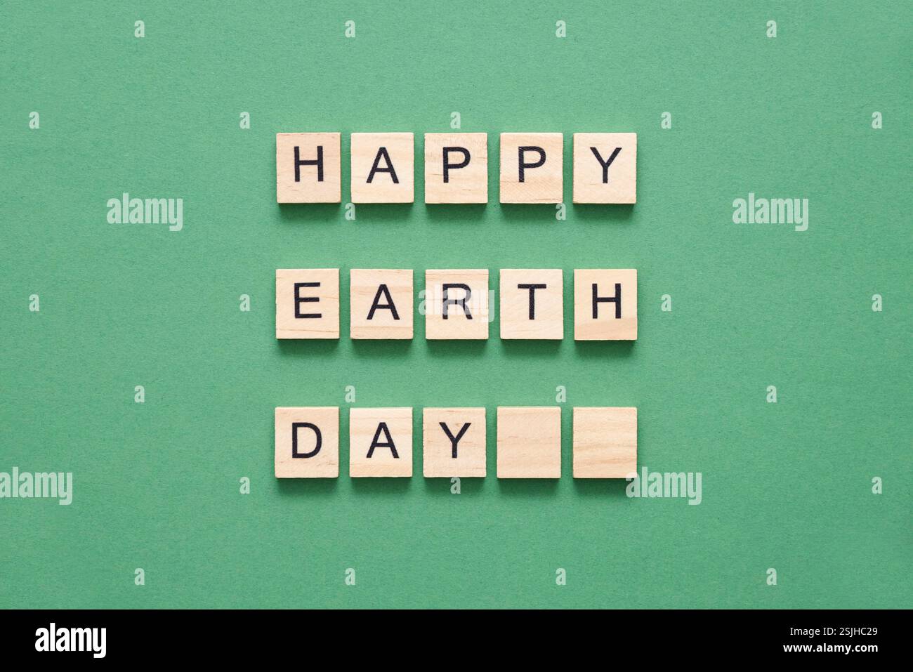 Wooden pieces with letters form the message Happy Earth Day, date ...
