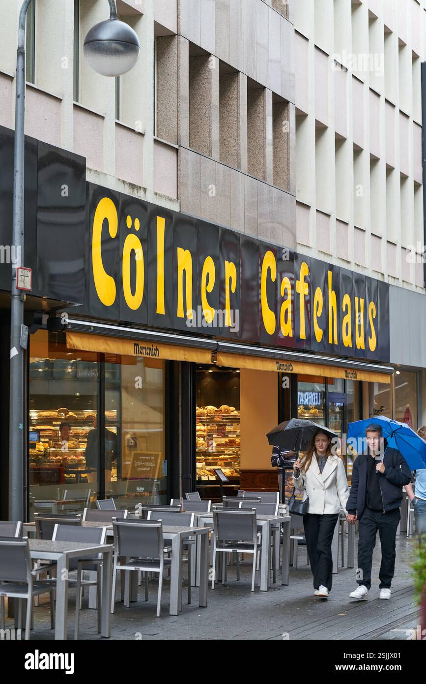Cologne city center with walkers in front of a café in rainy weather ...