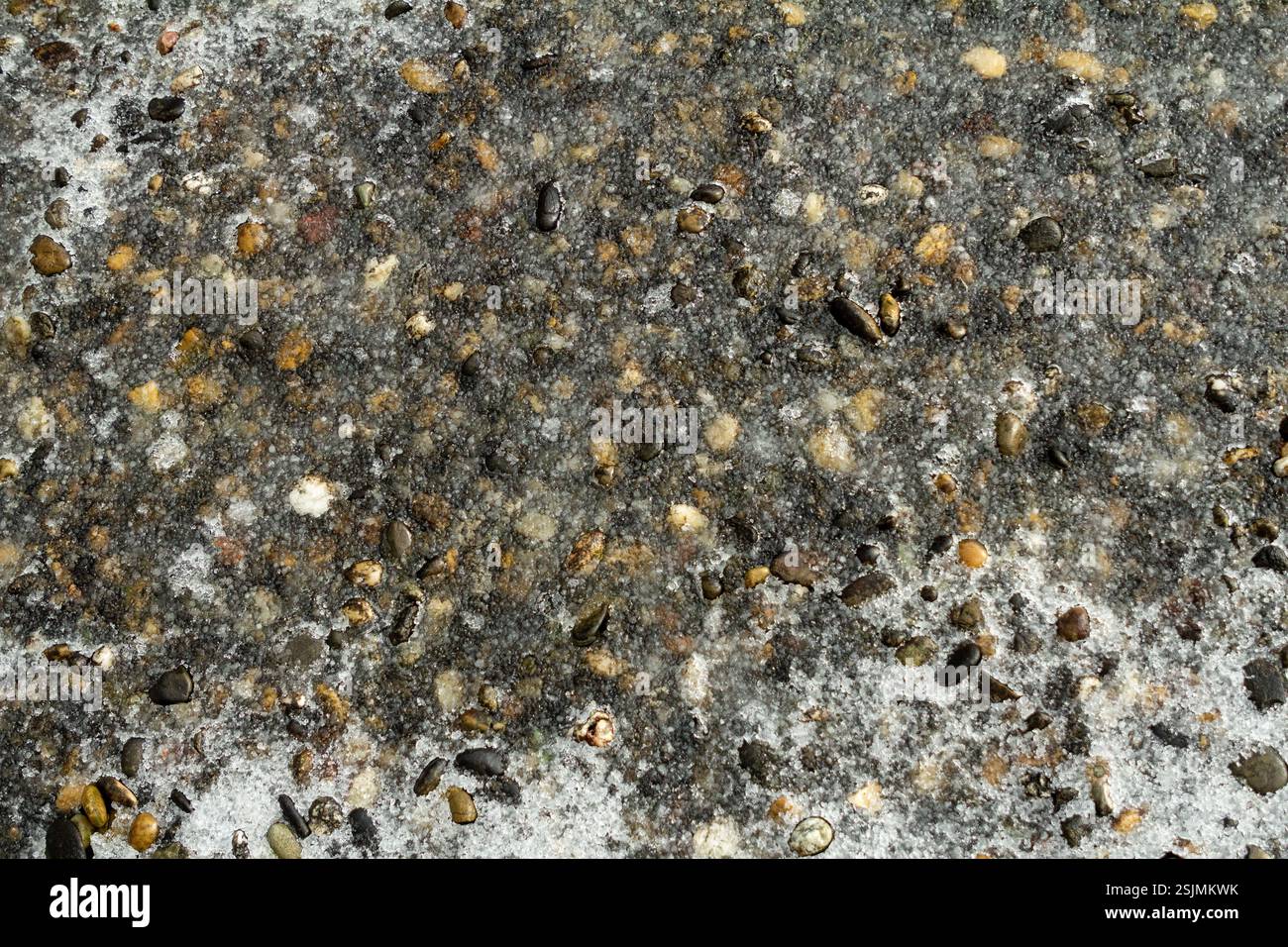 A close-up of frozen rocks covering a flat roof, part of a ballasted ...