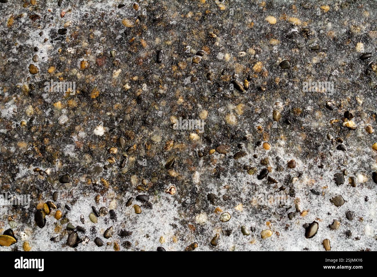 A close-up of frozen rocks covering a flat roof, part of a ballasted ...