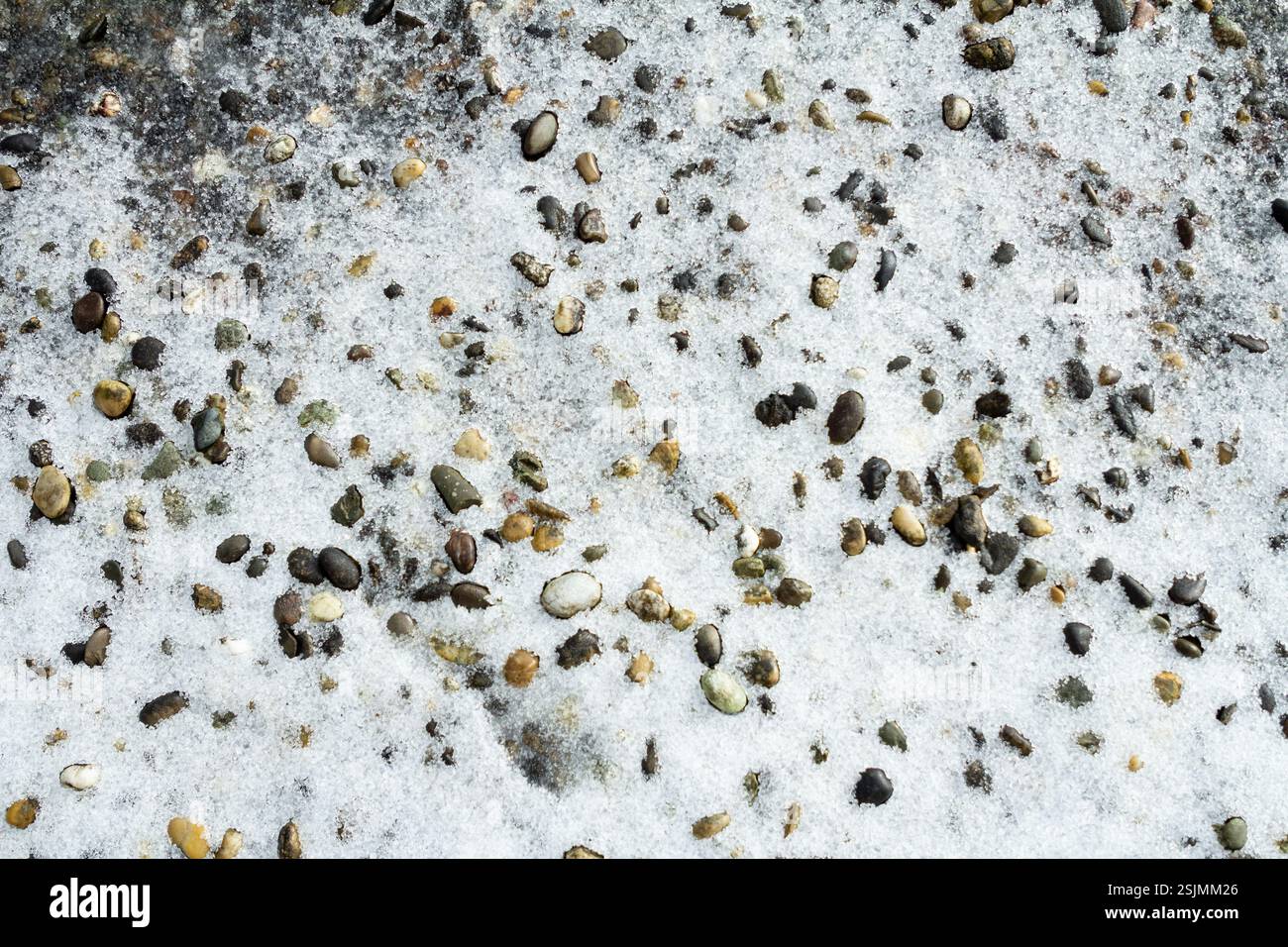 A close-up of frozen rocks covering a flat roof, part of a ballasted ...