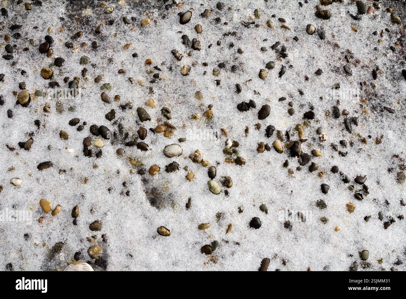 A close-up of frozen rocks covering a flat roof, part of a ballasted ...