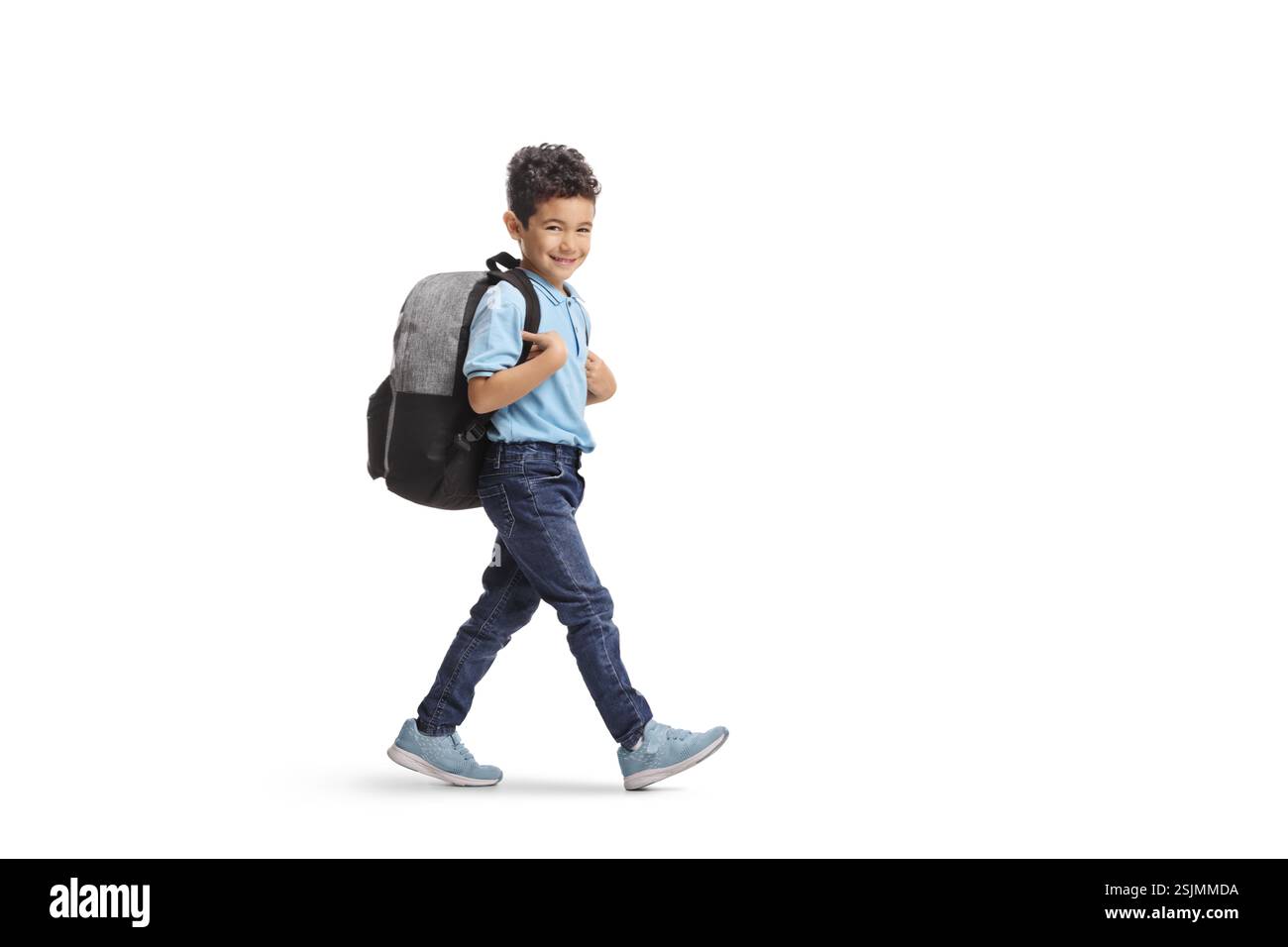 Kid with a backpack walking and smiling at camera isolated on white ...