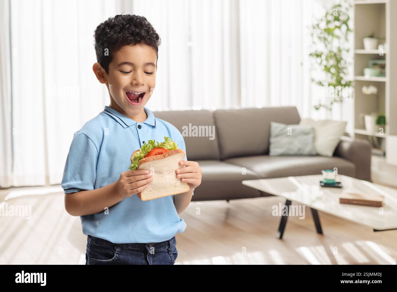 Hungry kid eating a sandwich at home Stock Photo - Alamy