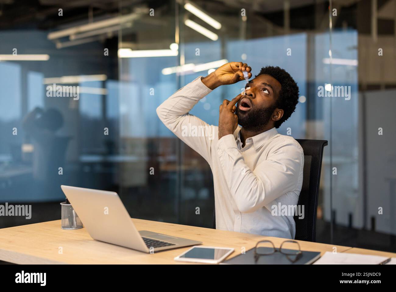 Eye pain, man drips medicine drops into his eyes. Office worker tired ...