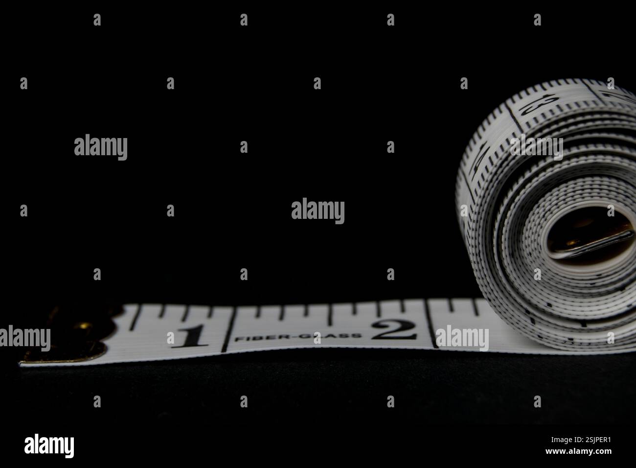 Close-up of a rolled white measuring tape with black markings ...