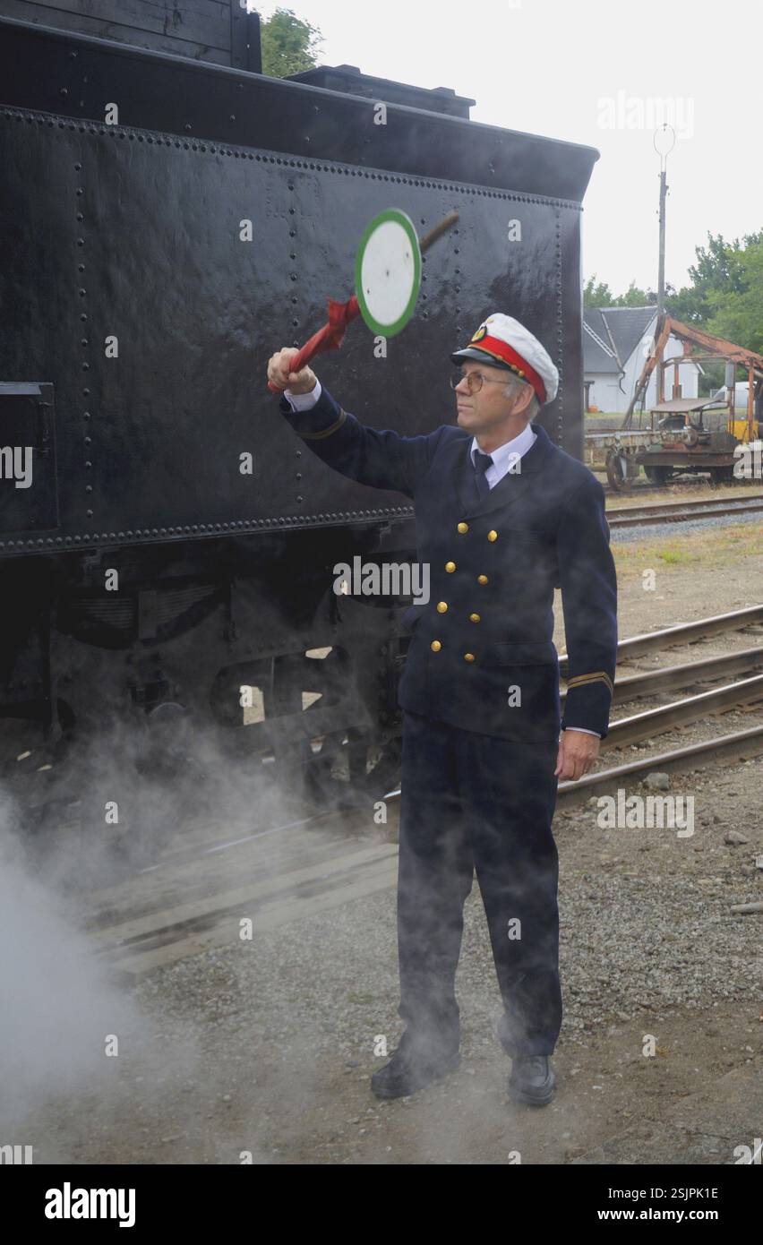 Station staff gives signal to the steam train on the museum railway ...