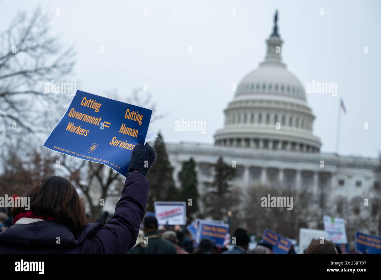 A demonstrator holds up a sign at a "Save the Civil Service" rally ...