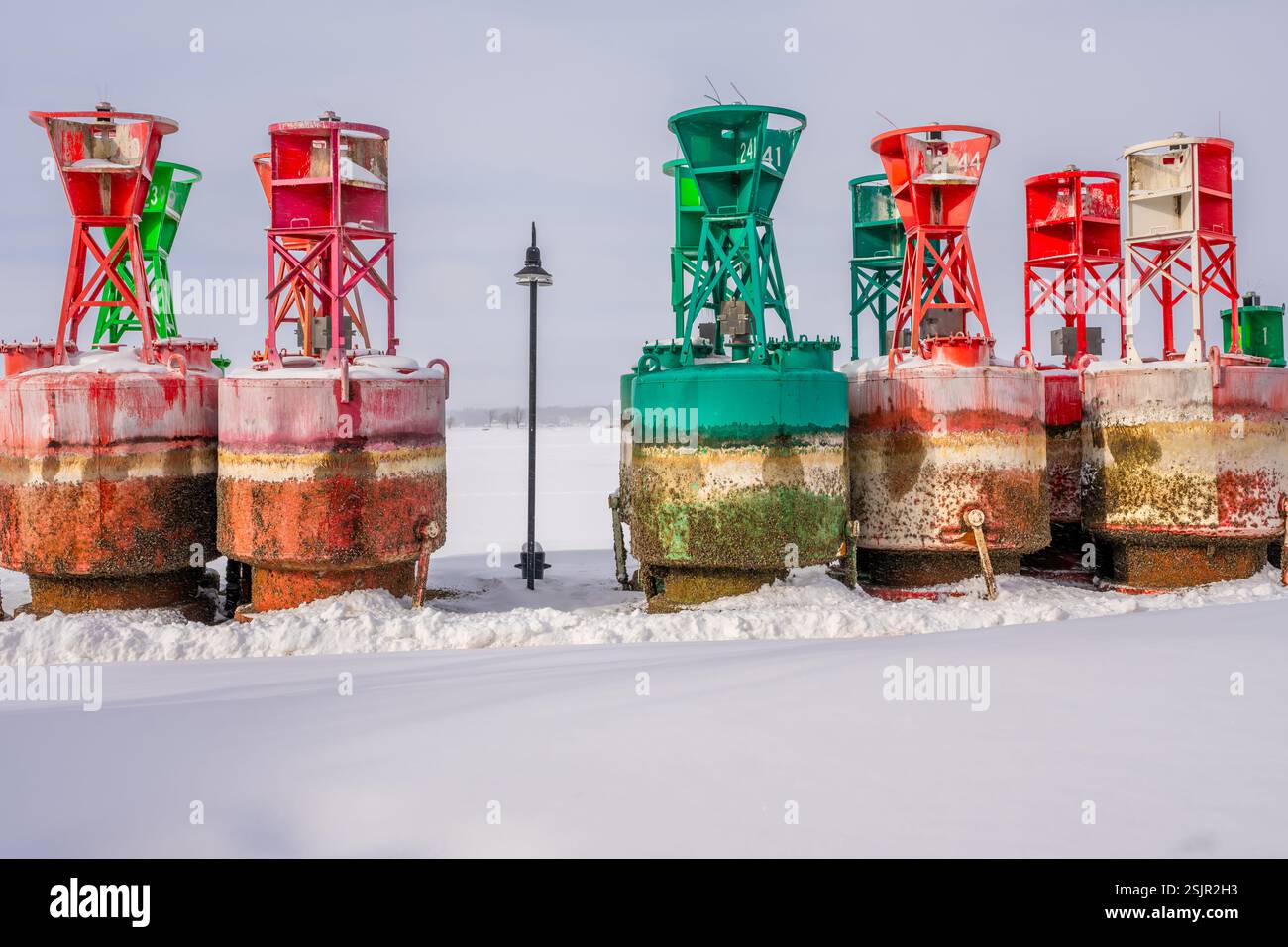 Snow covered red and green marine navigation buoys stored on land ...