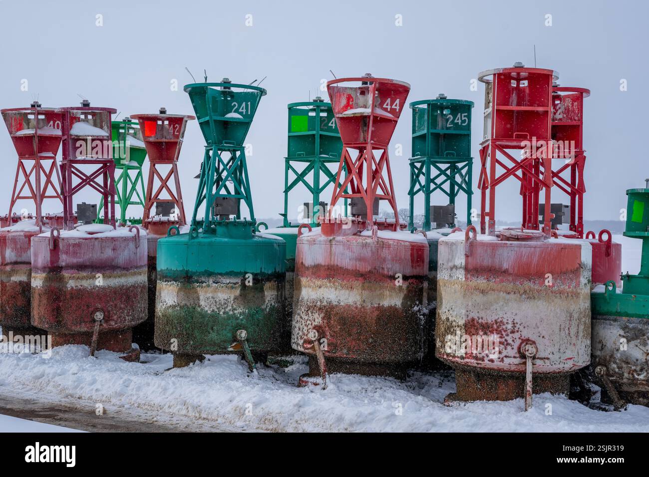 Snow covered red and green marine navigation buoys stored on land ...