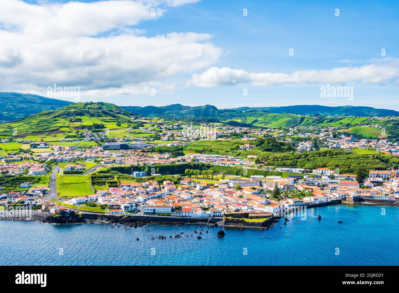 View of Horta town on ocean coast with green farming hills in ...
