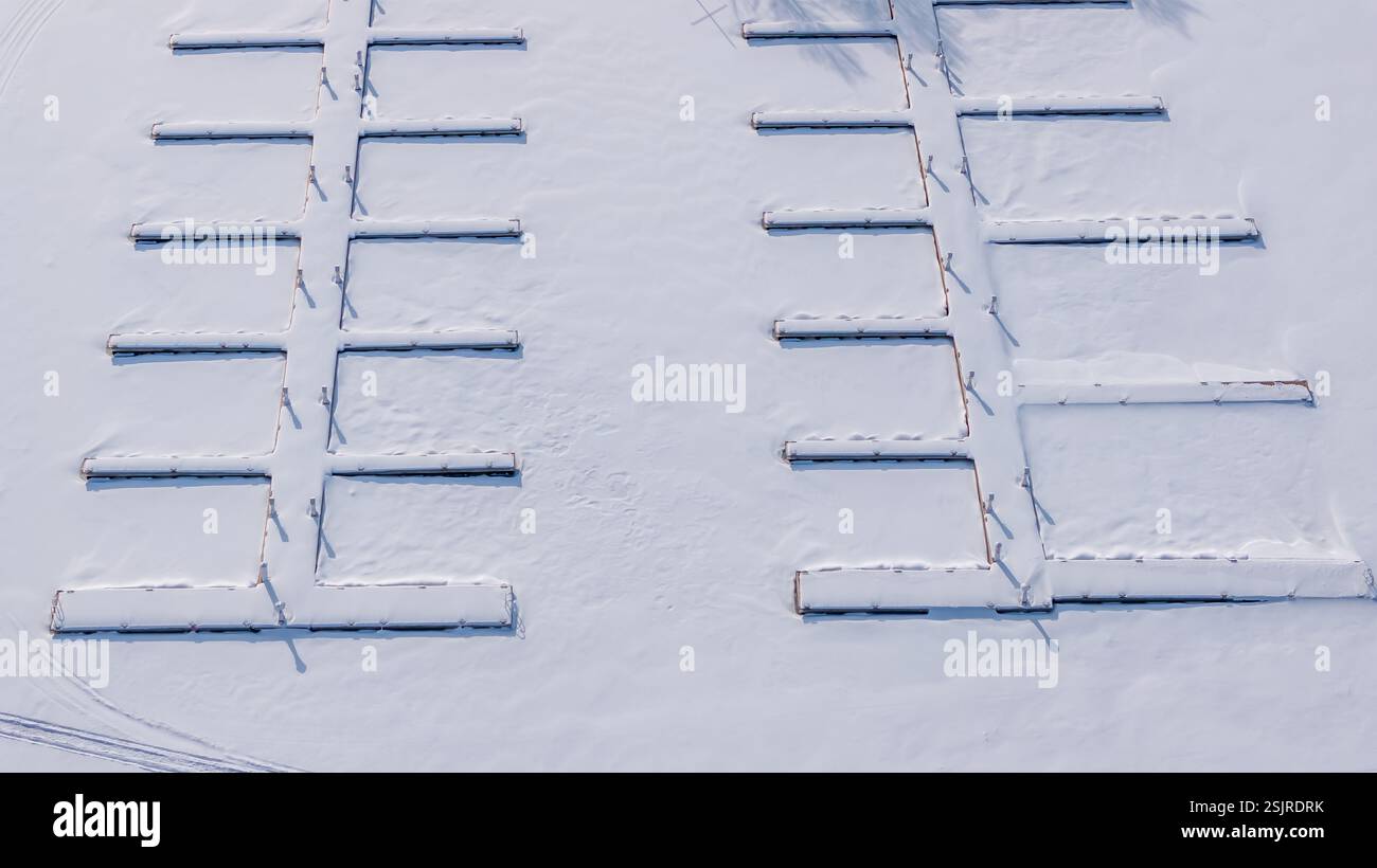 Winter aerial photo of frozen, snowy marina, docks on a lake, river or ...