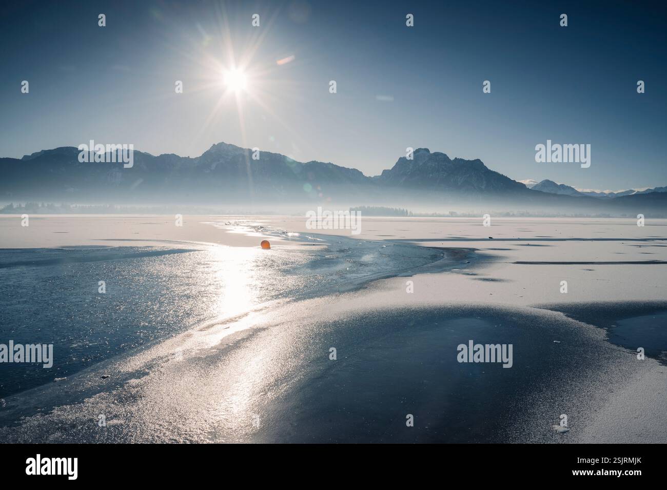 Frozen Forggensee against the light in bright winter weather with a red ...