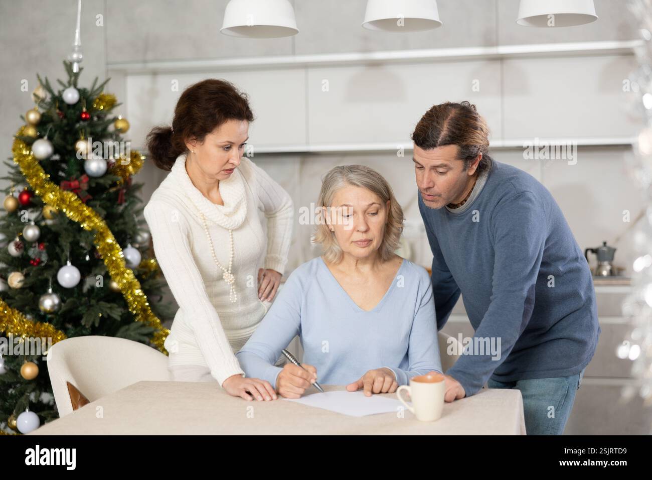 Man and woman help elderly mother make will and fill out document ...
