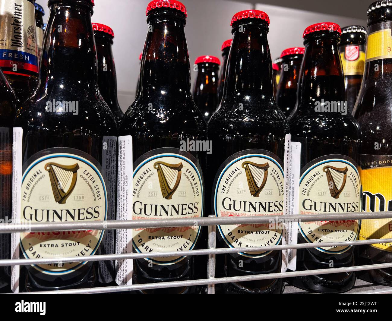 Kyiv, Ukraine - February 11, 2025: Dark Guinness beer bottles on display, featuring distinctive ...
