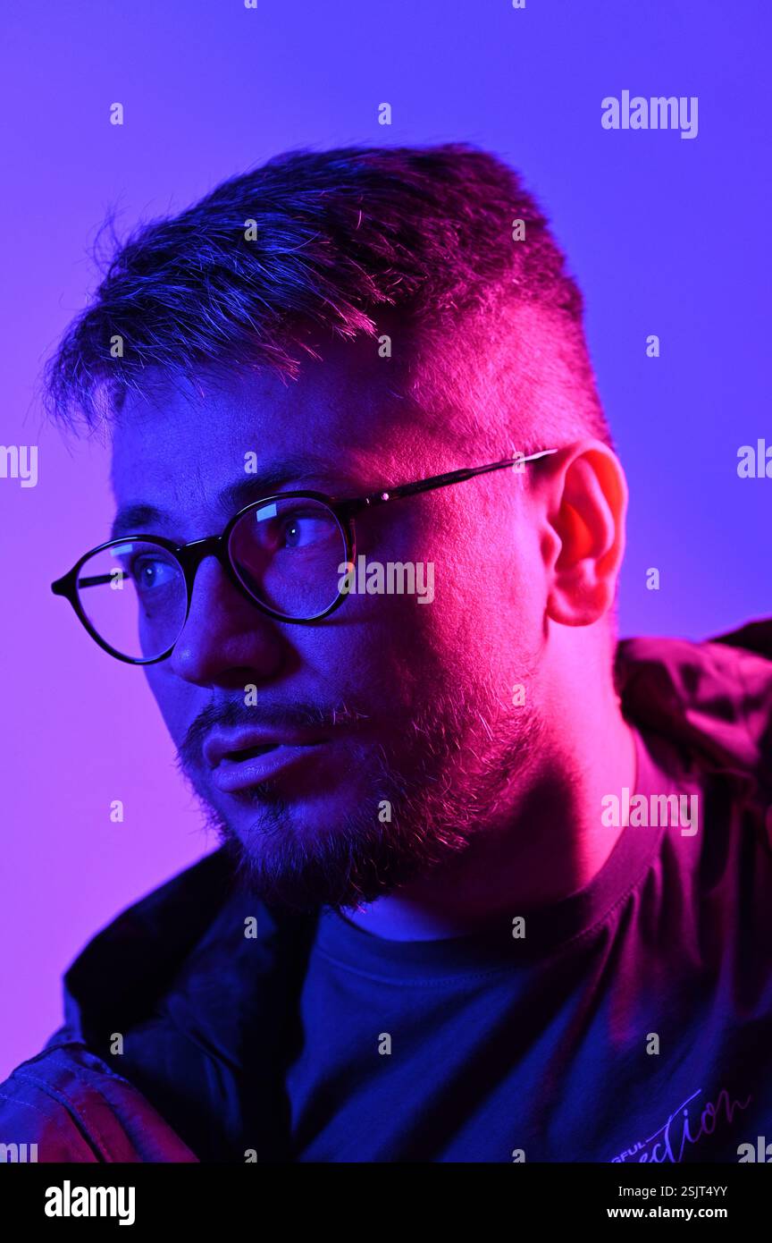 A stylish portrait of a young man with a small beard and glasses in ...