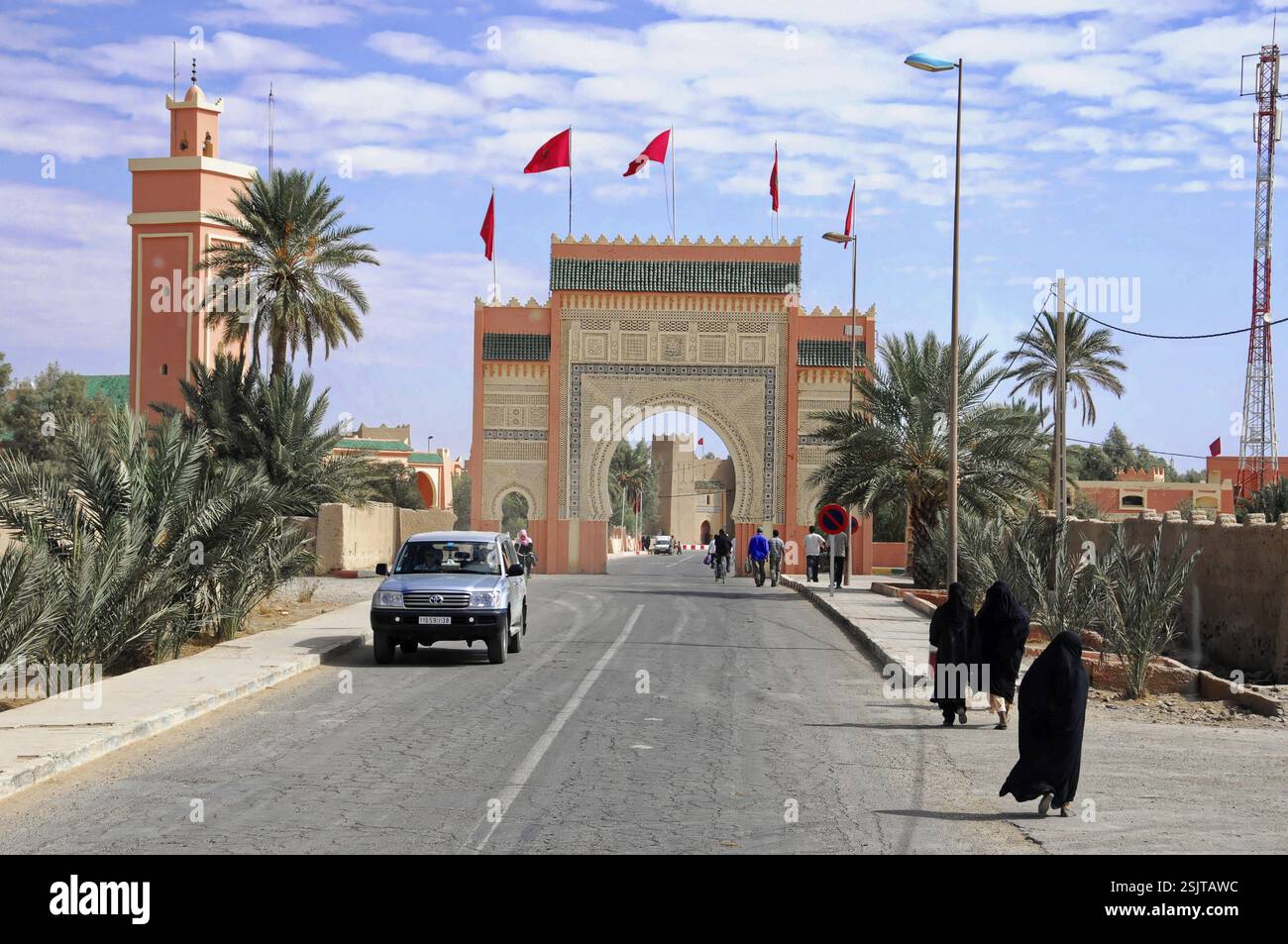 City gate of the desert city of Rissani, Historic city gate with passing vehicles under a sunny ...