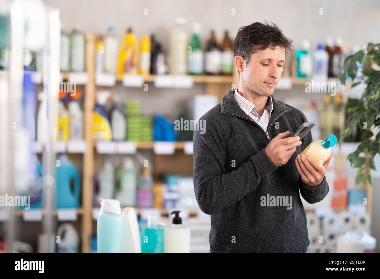 Middle-aged woman scanning QR-code on detergent at supermarket Stock ...