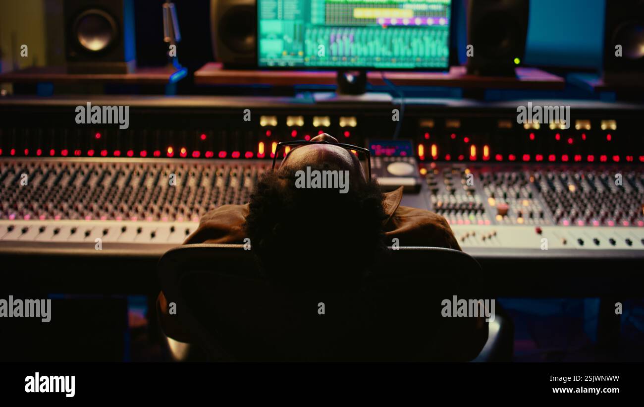 Sound designer relaxing on studio chair after mixing and mastering ...