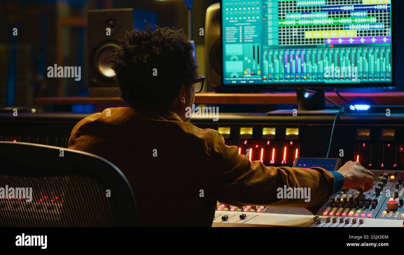 Sound designer uses mixing console and managing audio tracks, twisting ...