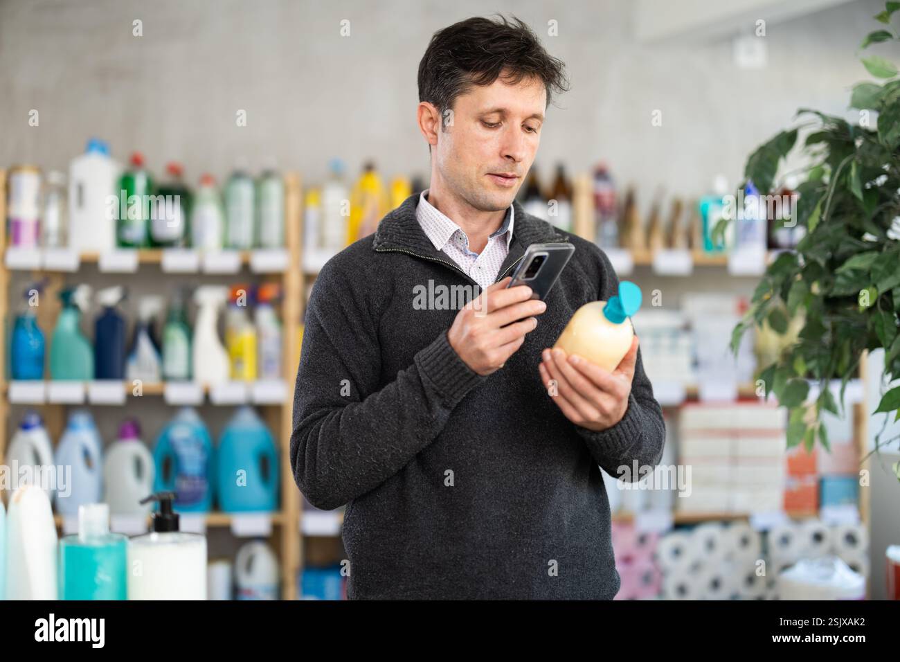 Middle-aged woman scanning QR-code on detergent at supermarket Stock ...