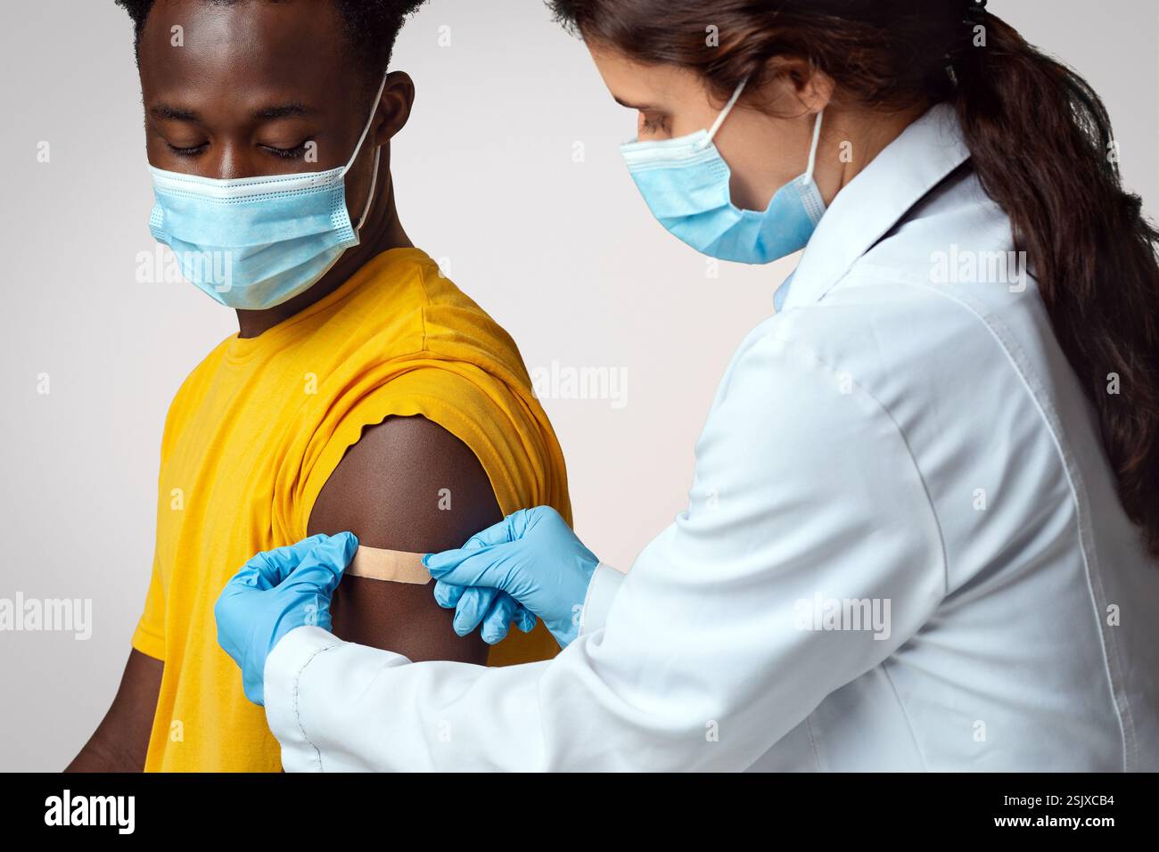 Female Nurse Applying Plaster On Black Guy's Shoulder After Injection ...