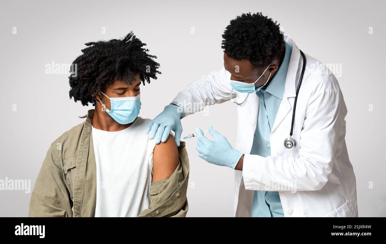 Black Doctor Making Vaccine Shot To Male Patient Wearing Medical Mask ...