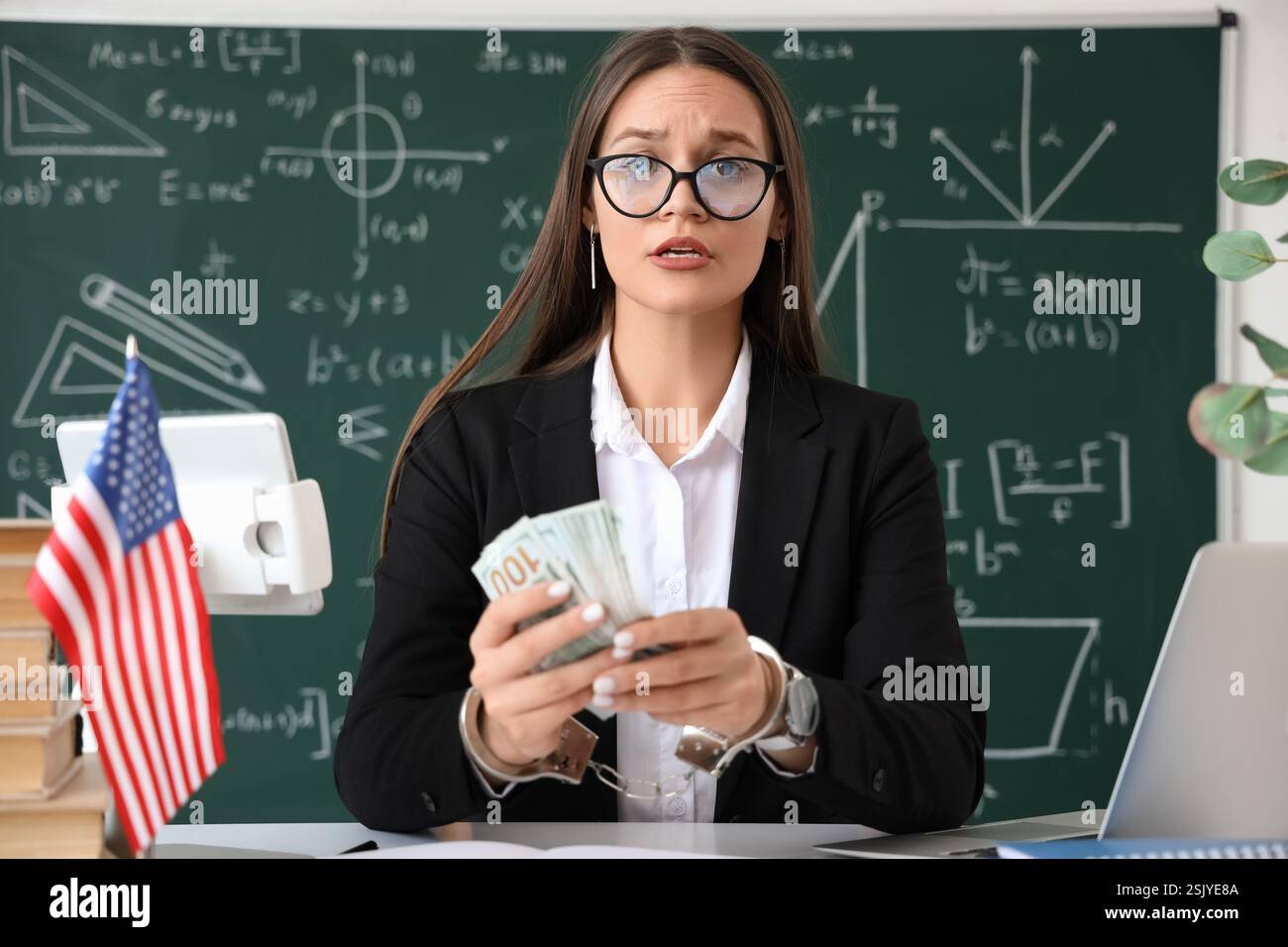 Handcuffed female teacher with bribe in classroom. Corruption concept ...