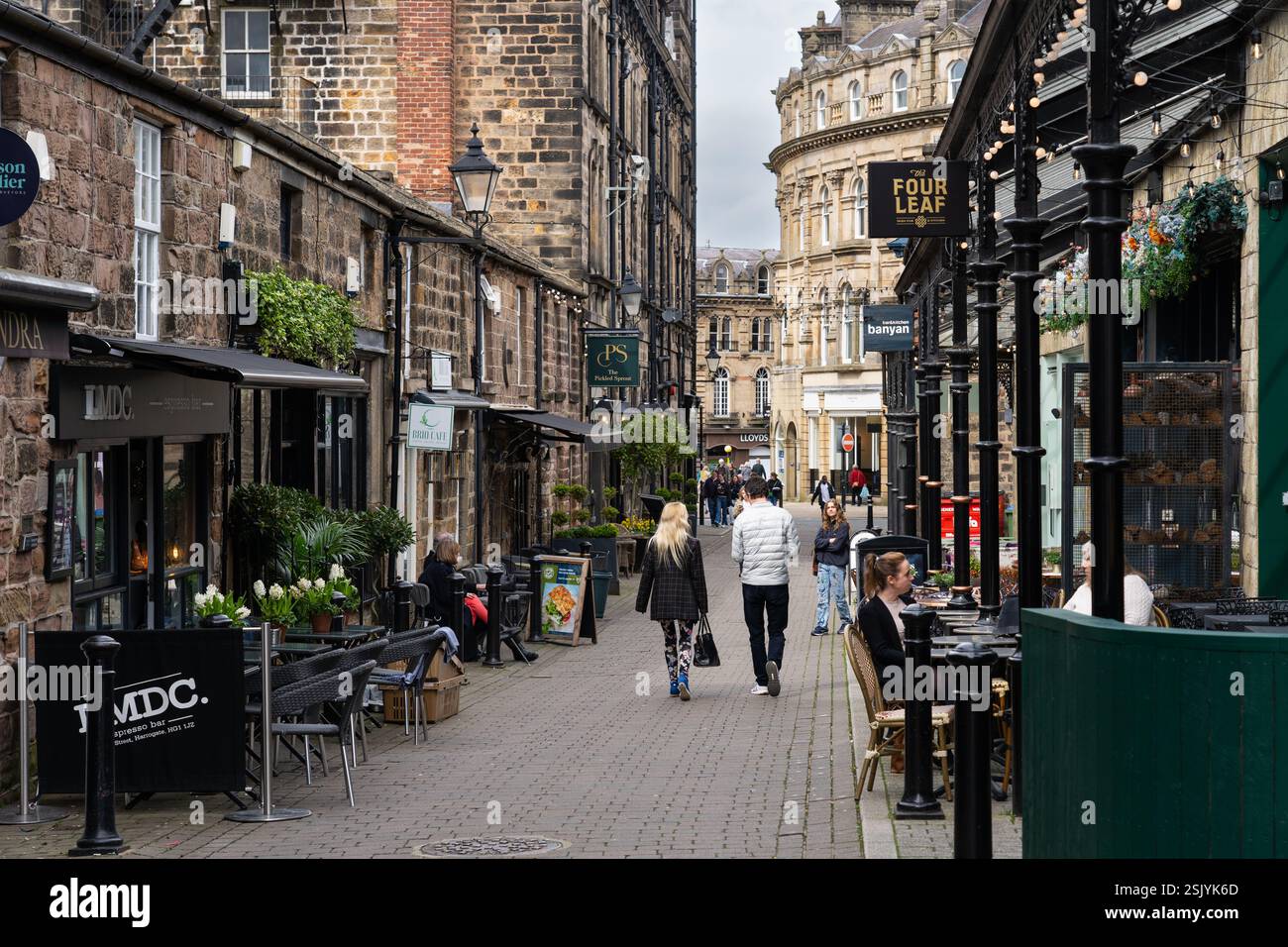 People walking past traditional sandstone buildings of cafes, bars and ...