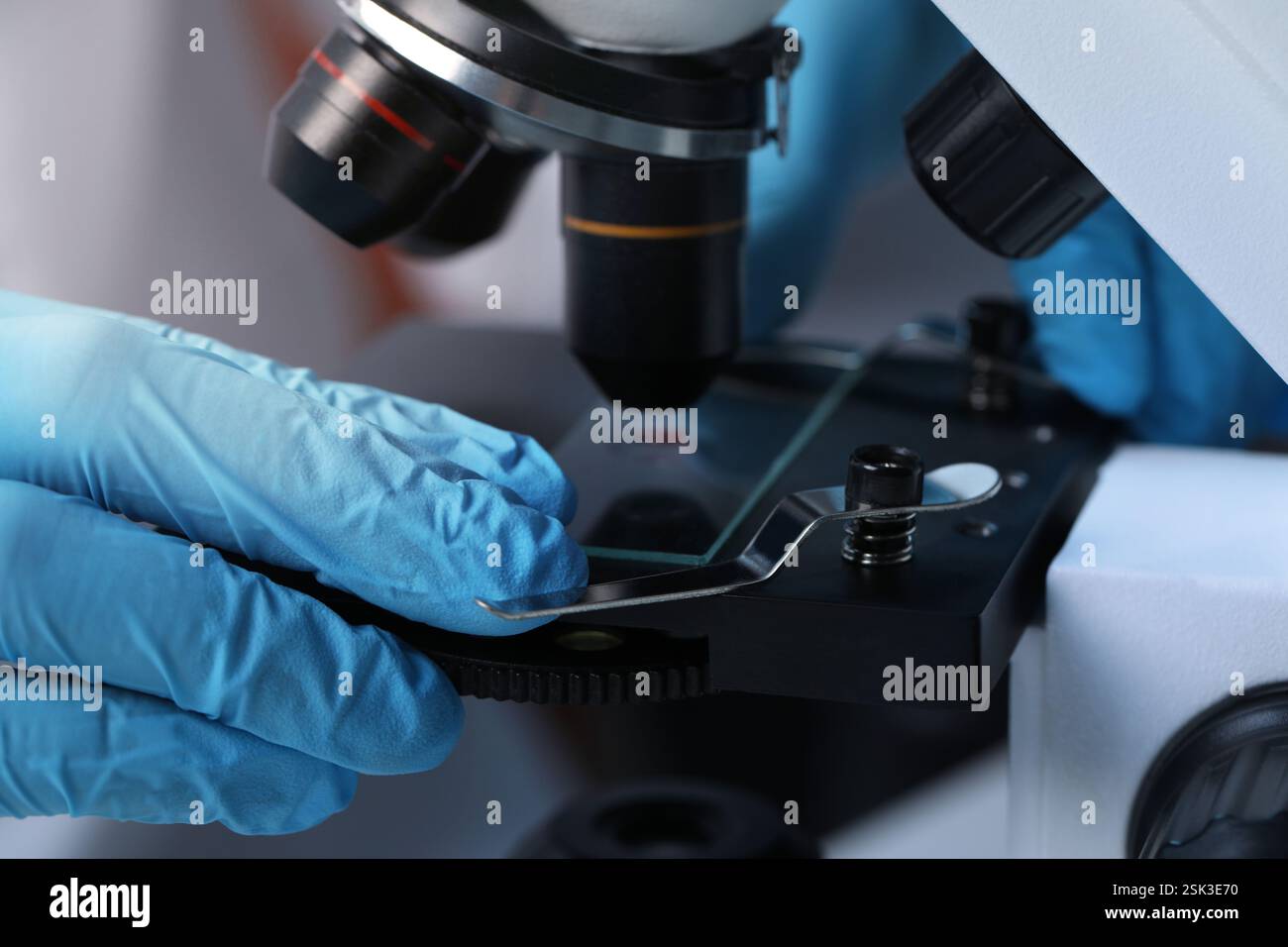 Scientist examining sample on slide under microscope, closeup Stock ...