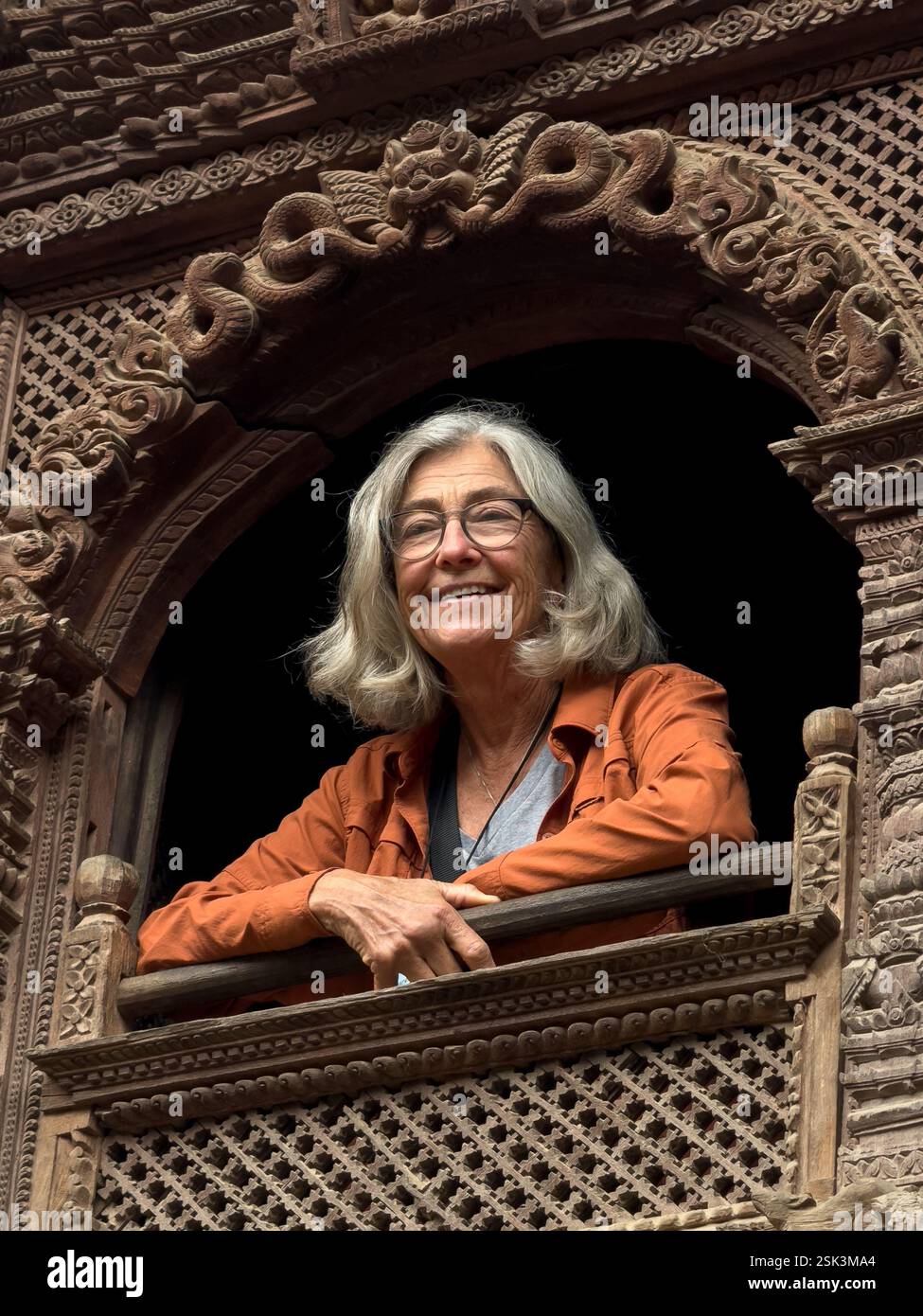 Tourist in an intricatly carved wooden window of the Sundari Chowk ...