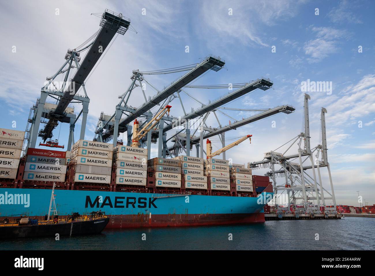 Gantry cranes extended over stacks of containers on a Maersk cargo ship ...