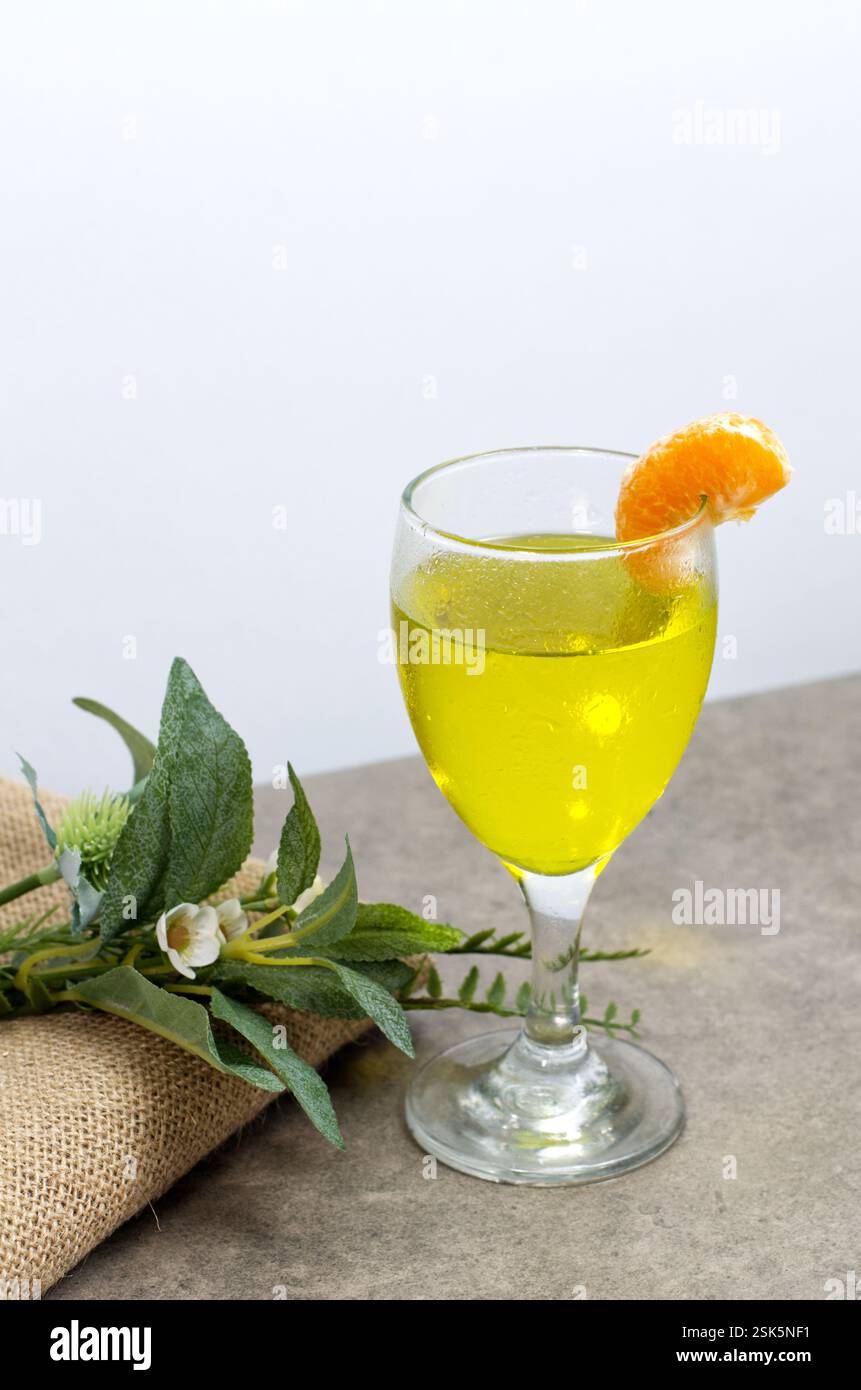 Glass of Yellow Beverage with Orange Slice and Greenery Arrangement ...