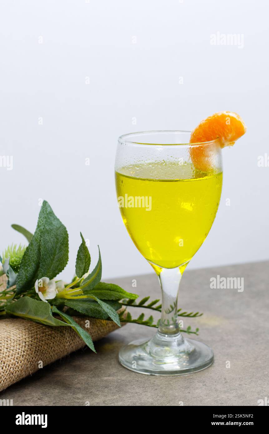 Glass of Yellow Beverage with Orange Slice and Greenery Arrangement ...