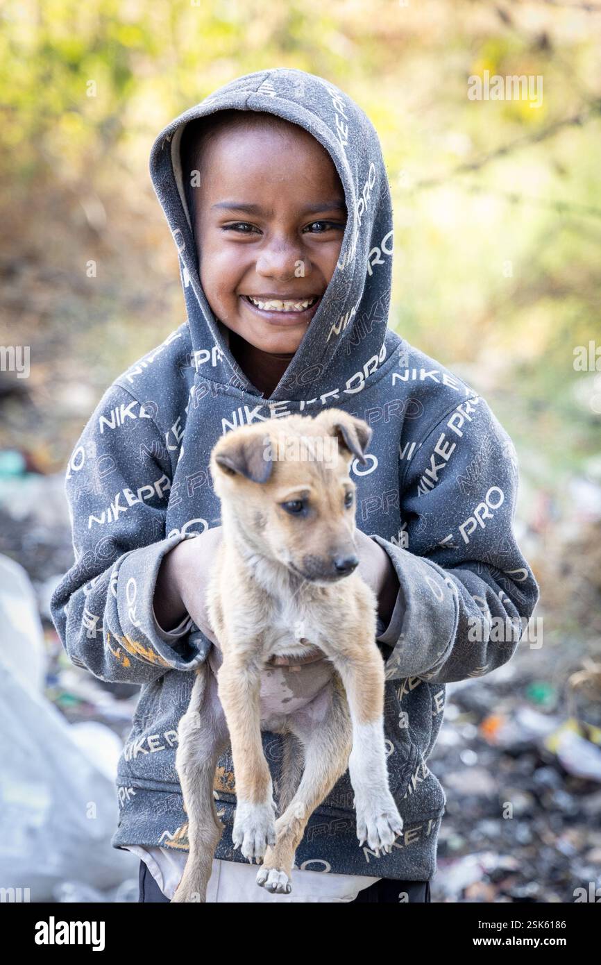 innocent poor garbage collecting kid with cute smile and dog in hand at ...