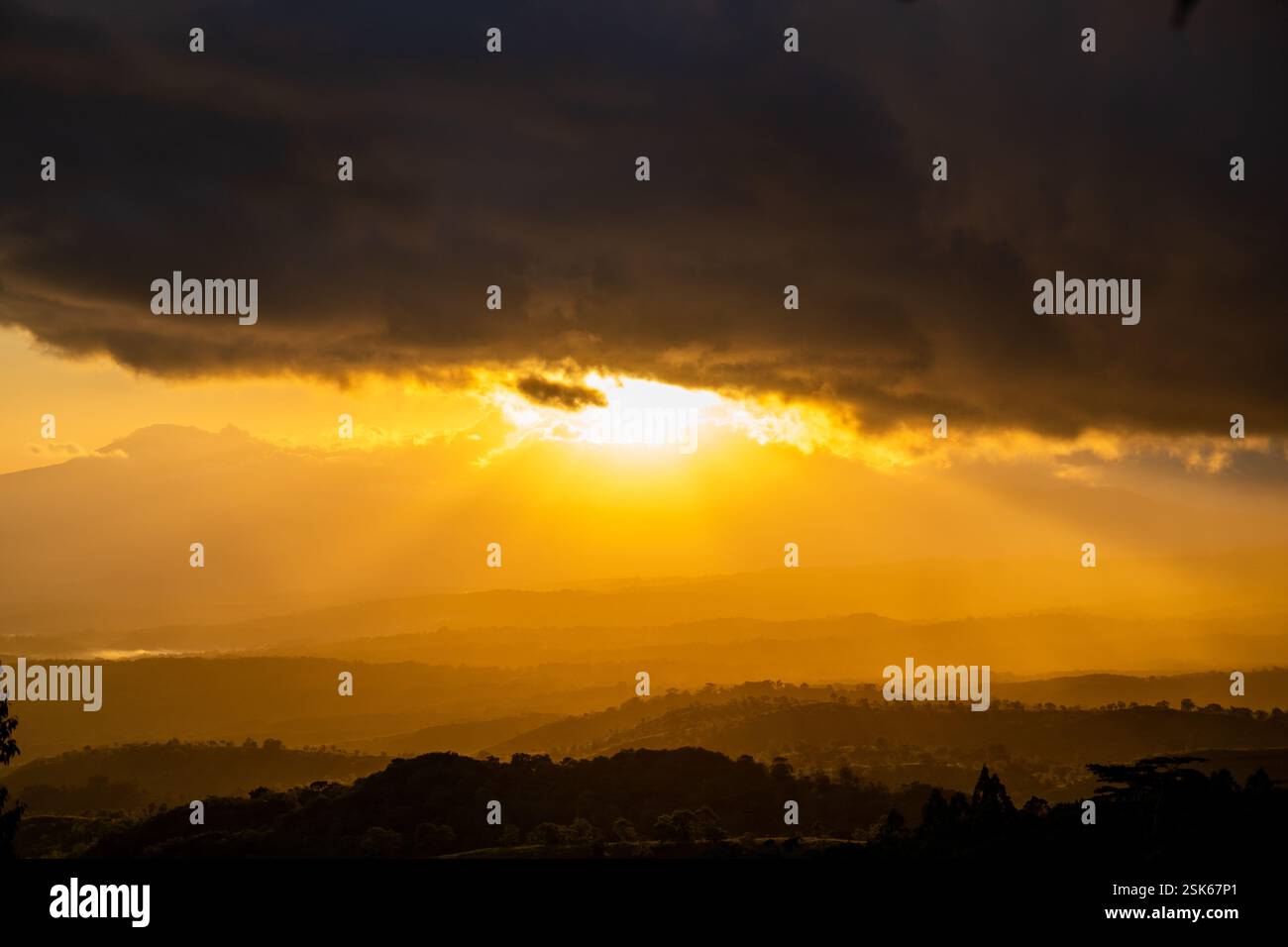 Golden Sunset Over Rolling Hills with Dramatic Dark Clouds and Sun Rays ...