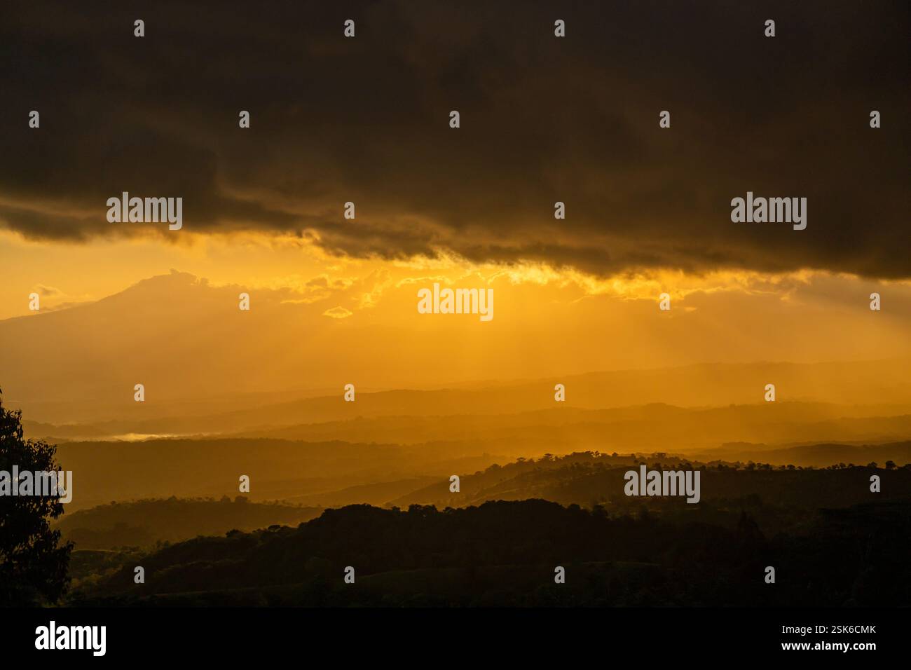Golden Sunset Over Rolling Hills with Dramatic Dark Clouds and Sun Rays ...