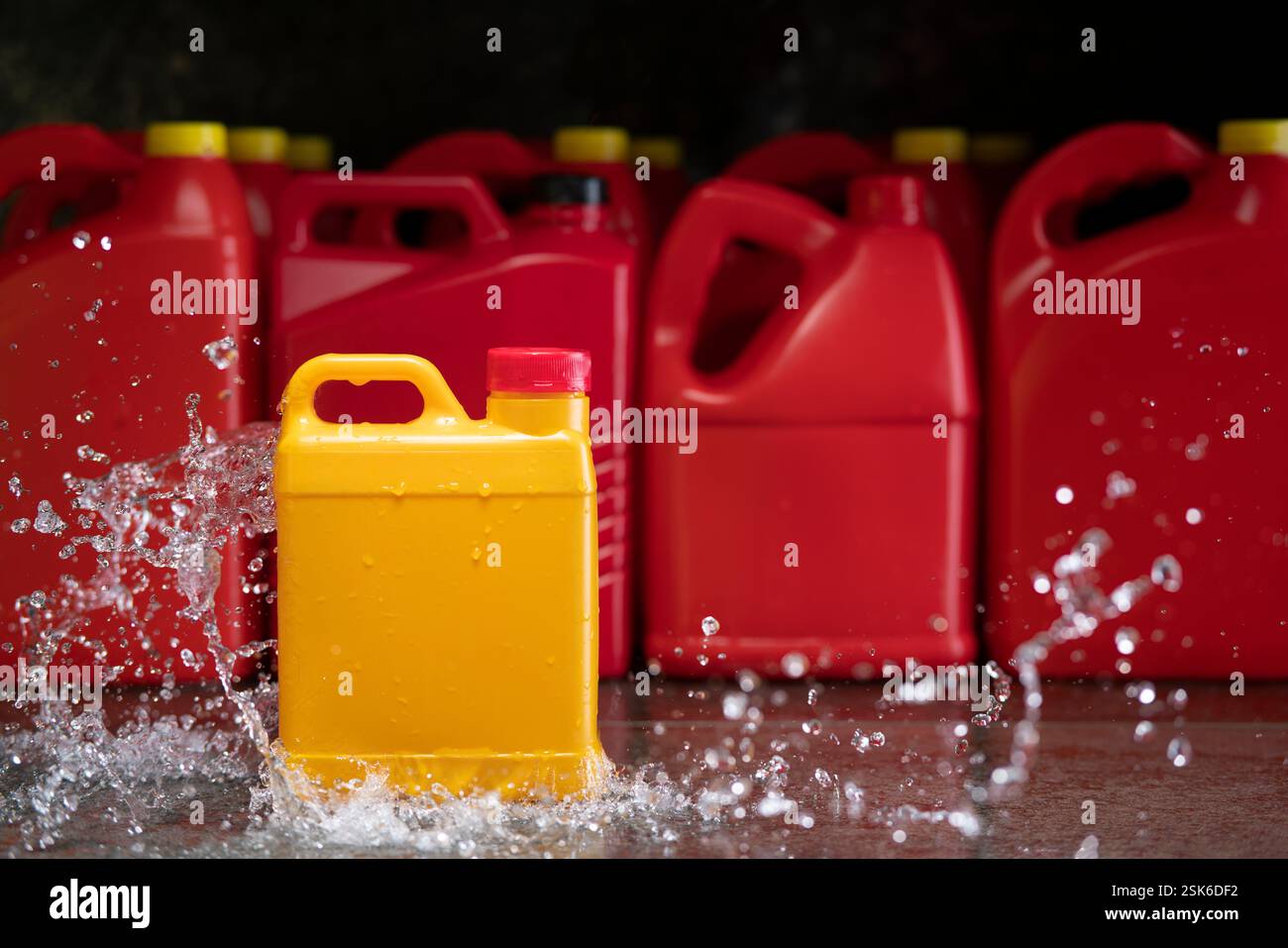 Front view of yellow plastic motor oil bottle splashed by stream of ...
