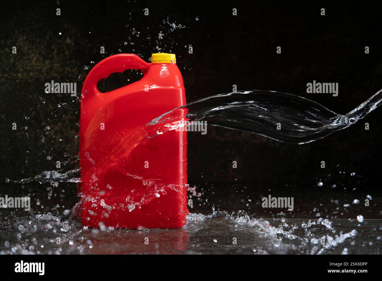 Front view of red plastic motor oil bottle splashed by stream of water ...