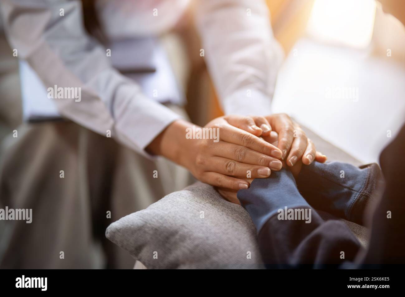 A close-up of a caring psychologist holding a patient's hand to comfort ...
