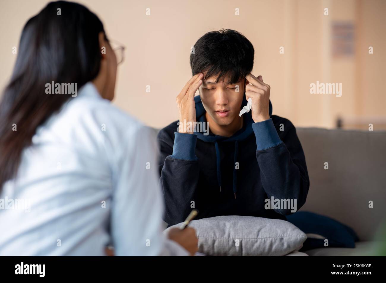 A stressed, crying young Asian man talks with his psychologist in the ...
